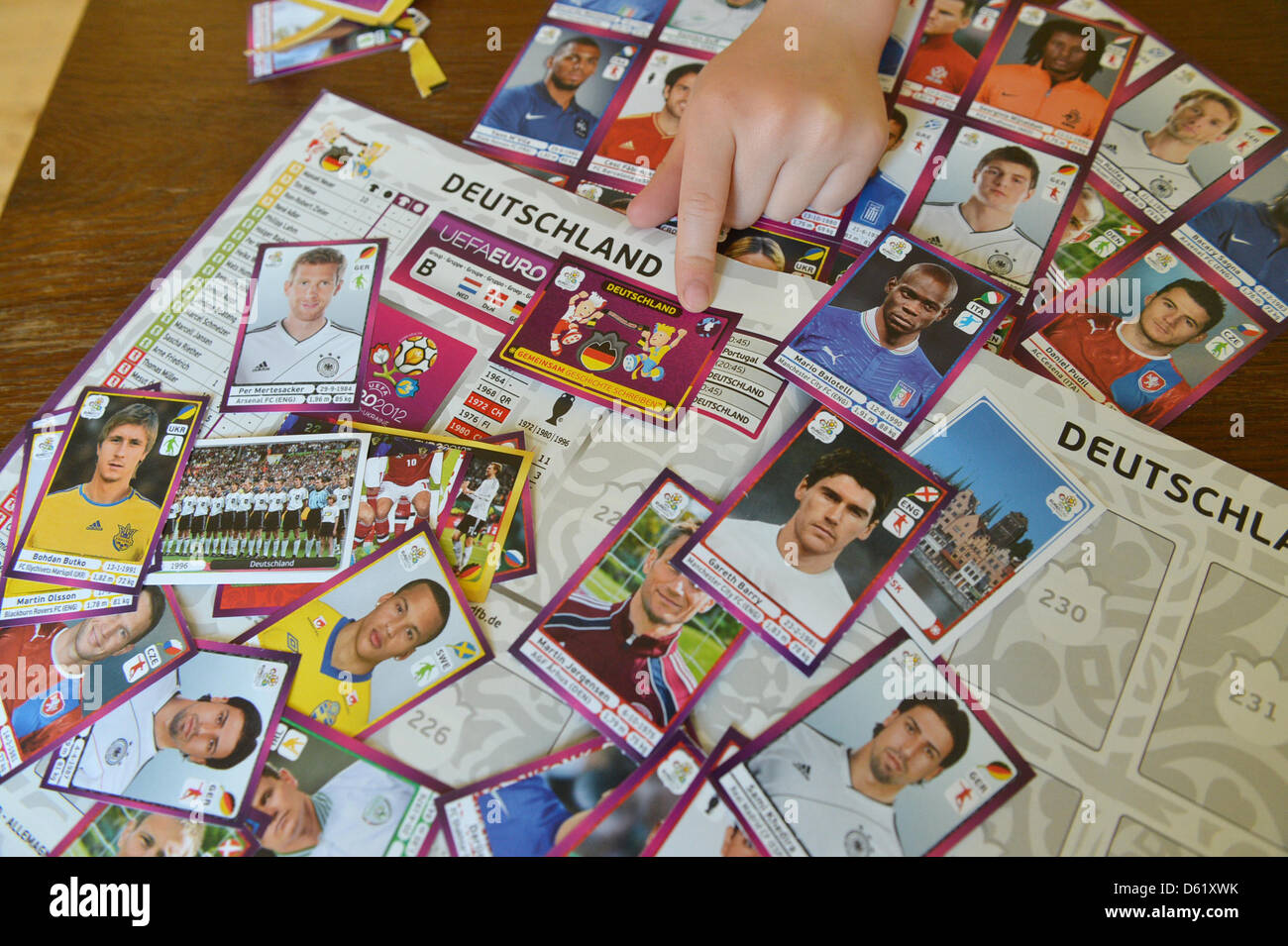 A boy opens a Panini-sticker package and points to a sticker featuring ...