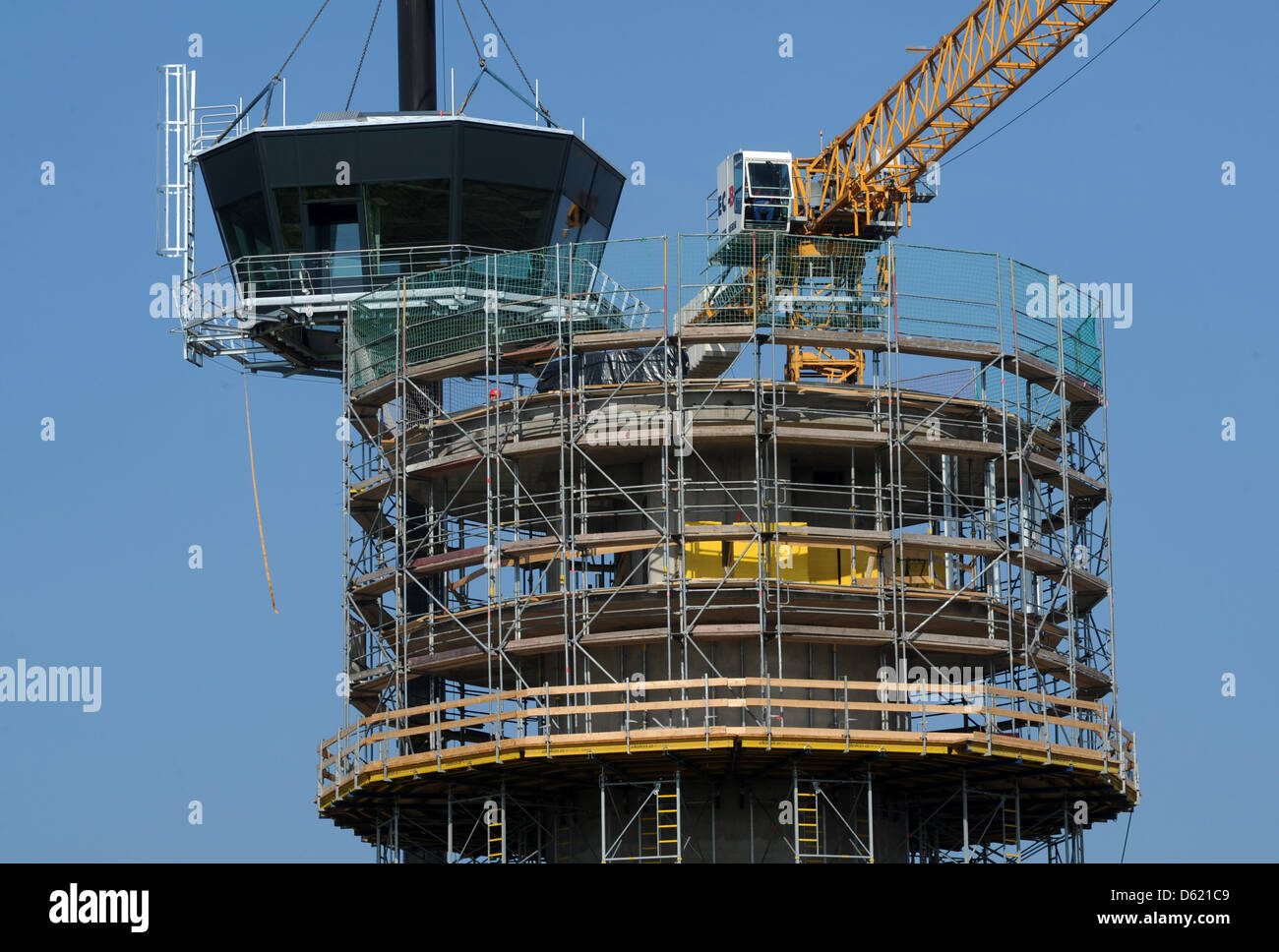 A turret is lifted by a crane onto the control tower at the new airport ...