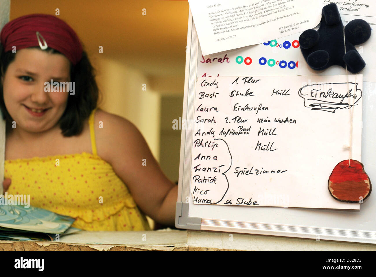10 year old Laura stands next to a chore list for the older children of ...