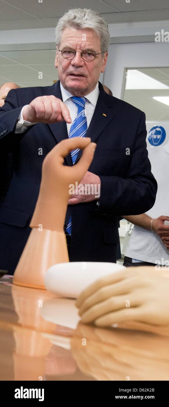 German President Joachim Gauck stands behind a prosthetic hand during a ...