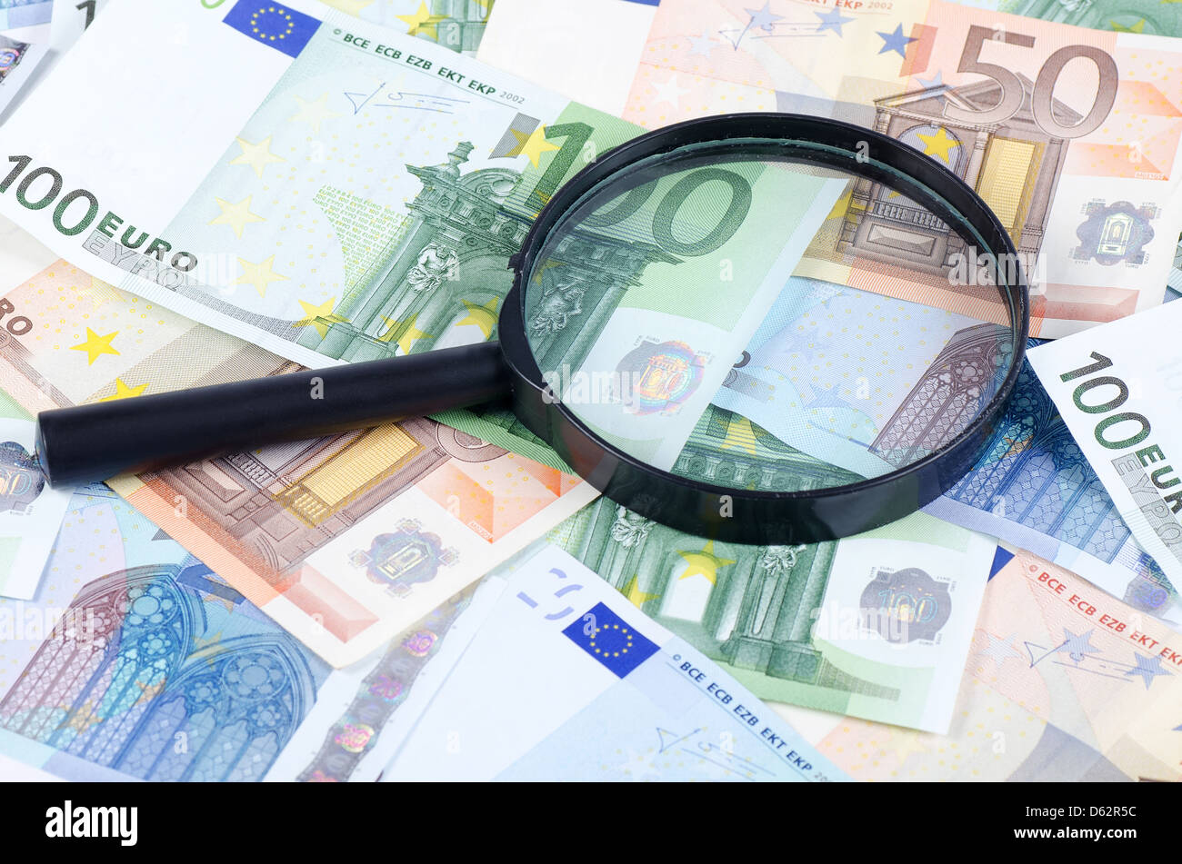 Magnifying glass lying on banknotes Stock Photo - Alamy
