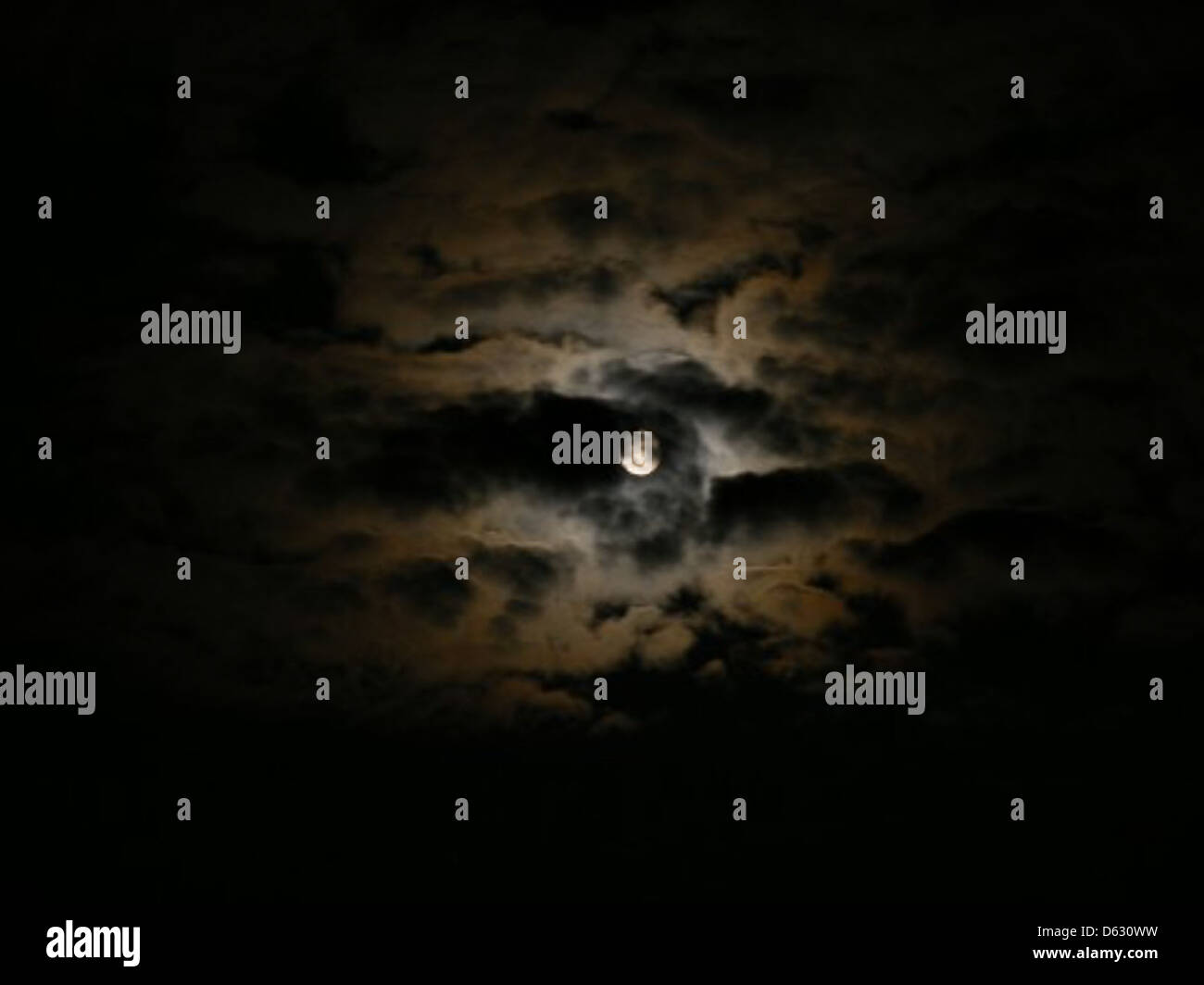 A photograph of the moon partially obscured by clouds, creating a ...