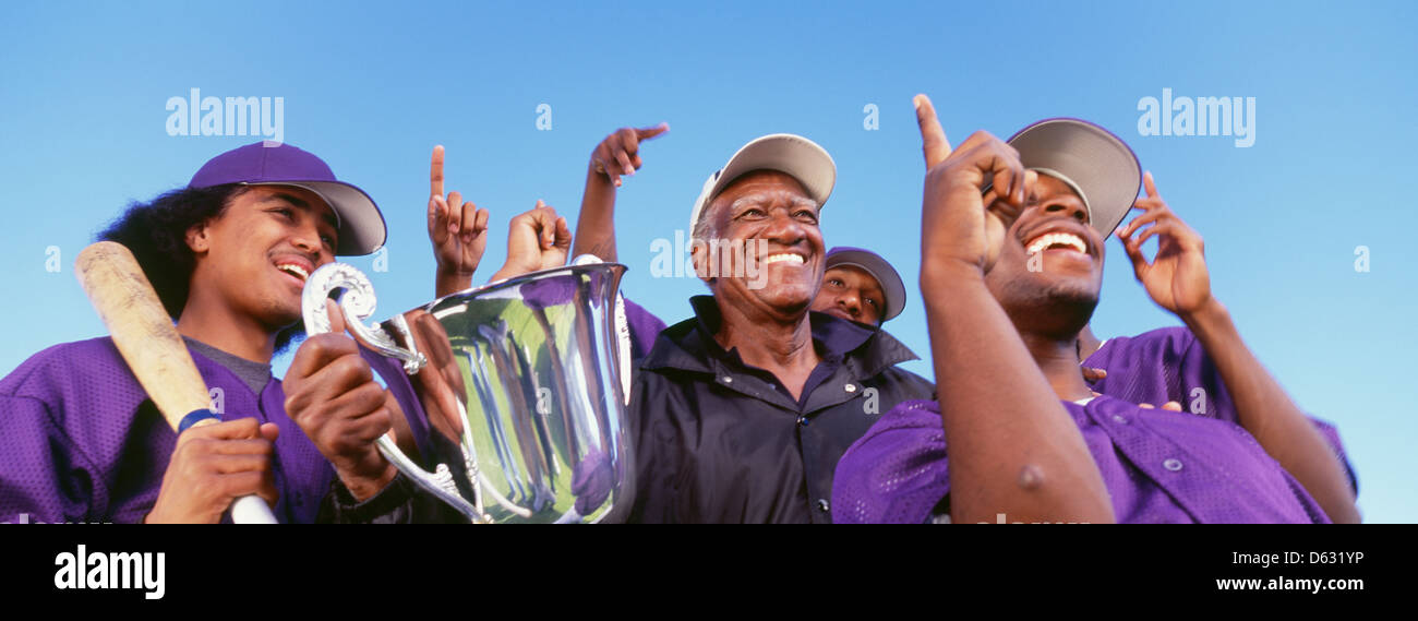 Panoramic shot of cheerful baseball players with trophy celebrating ...