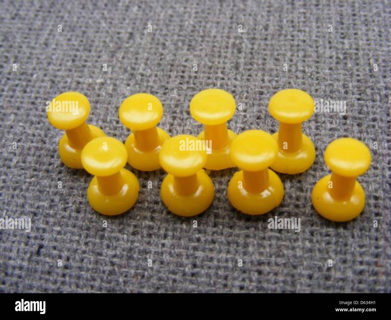 A close-up of a yellow push pin, commonly used in offices and for map ...