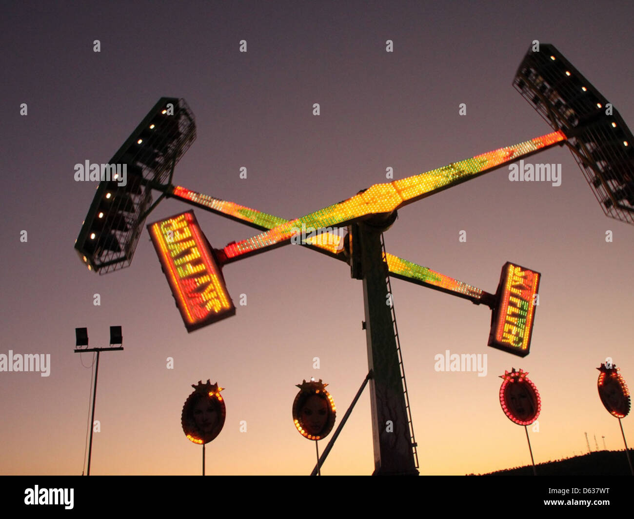 This image showcases a SkyFlyer swing ride illuminated at night ...