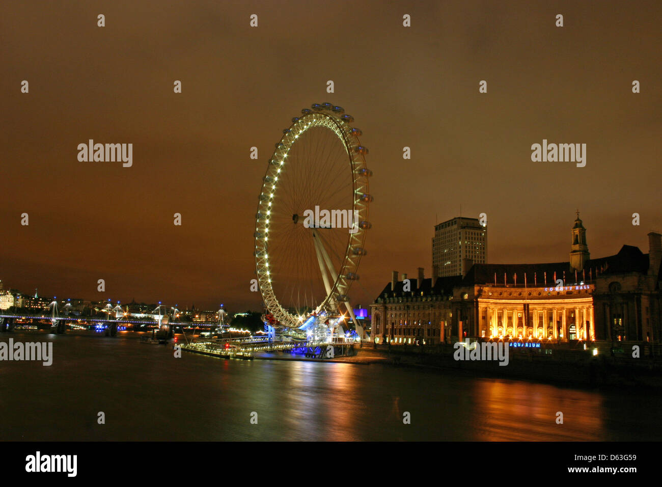The London Eye lit up at night next to County Hall, next to the river ...