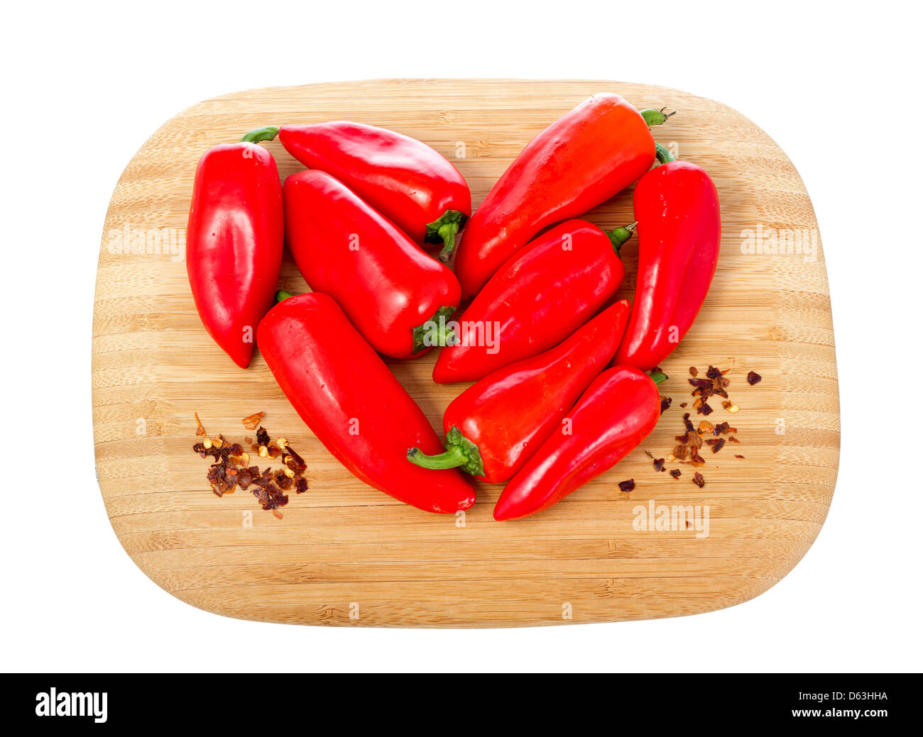 Heart shape made of red hot peppers on wooden cutting board isolated on ...