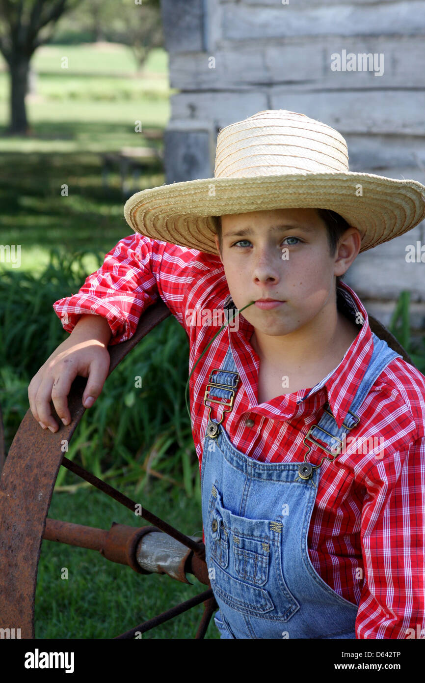A young farmer boy next to antique farm equipment Stock Photo - Alamy