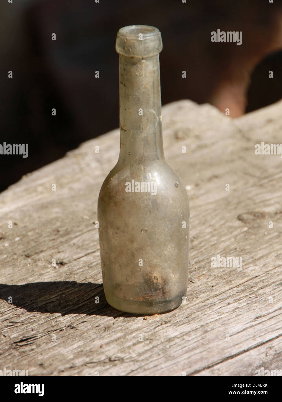 A close-up of a very old, dusty glass bottle, showing the wear and tear ...
