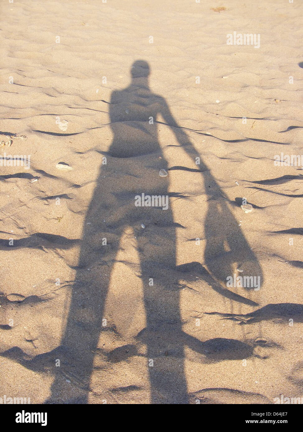 A photograph capturing a shadow of a woman on the beach. The light ...