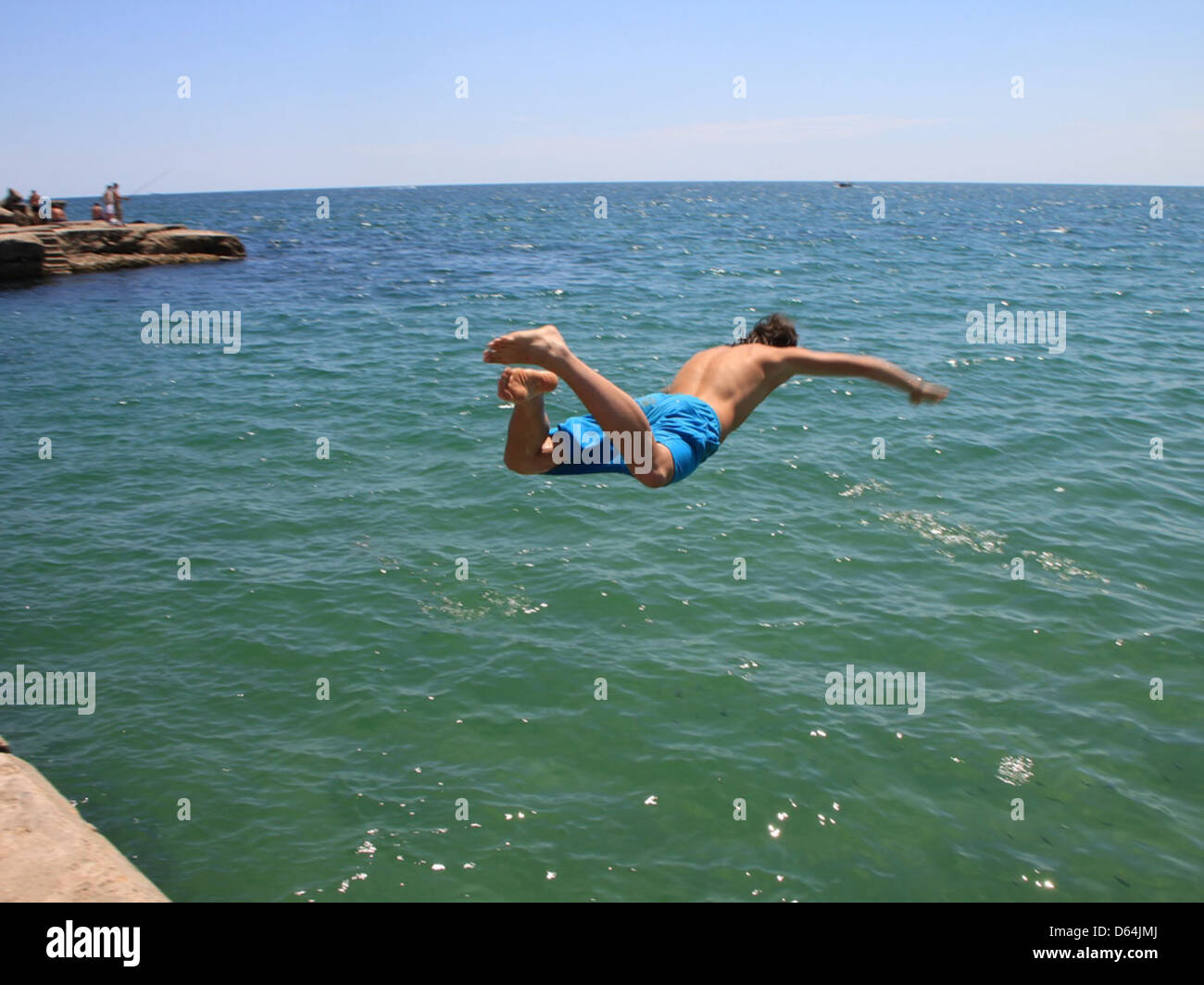 A photo of a man jumping into the water, creating splashes as he dives ...