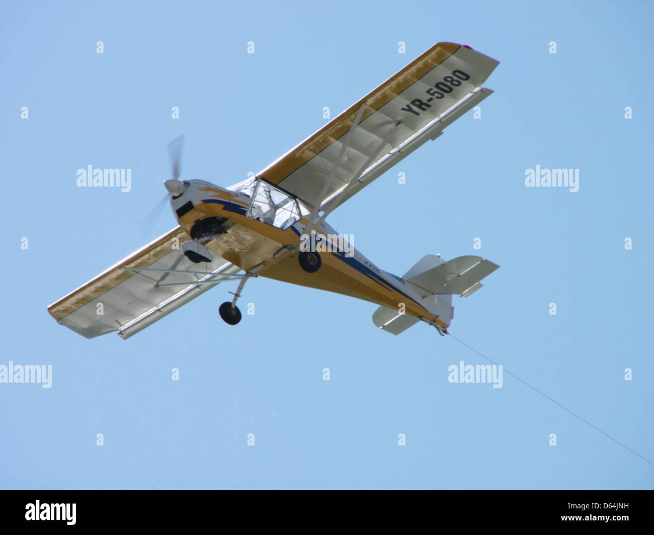 This image shows a small airplane flying through a clear blue sky ...