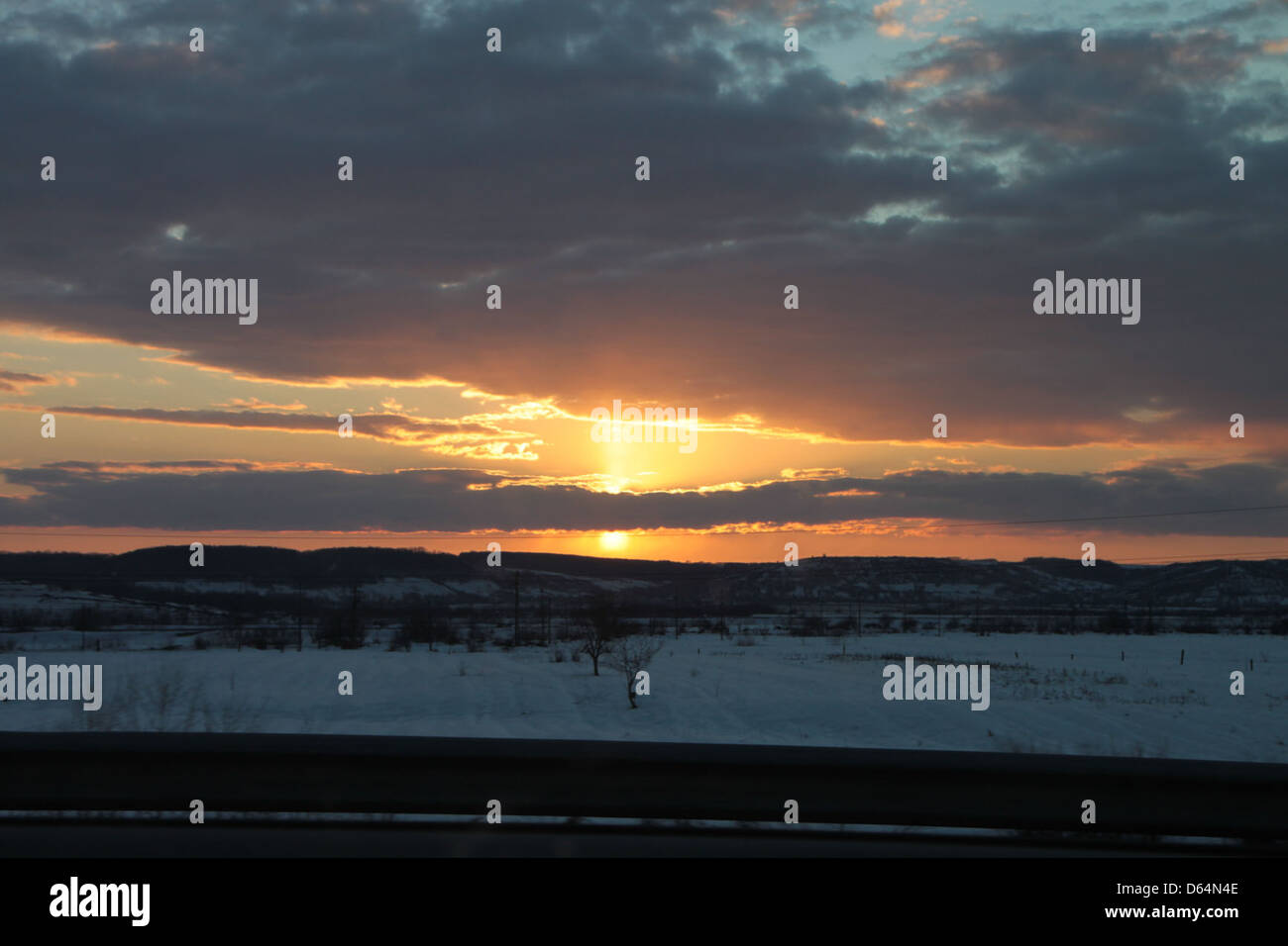 A dramatic winter sunset with dark red sun rays piercing through the ...