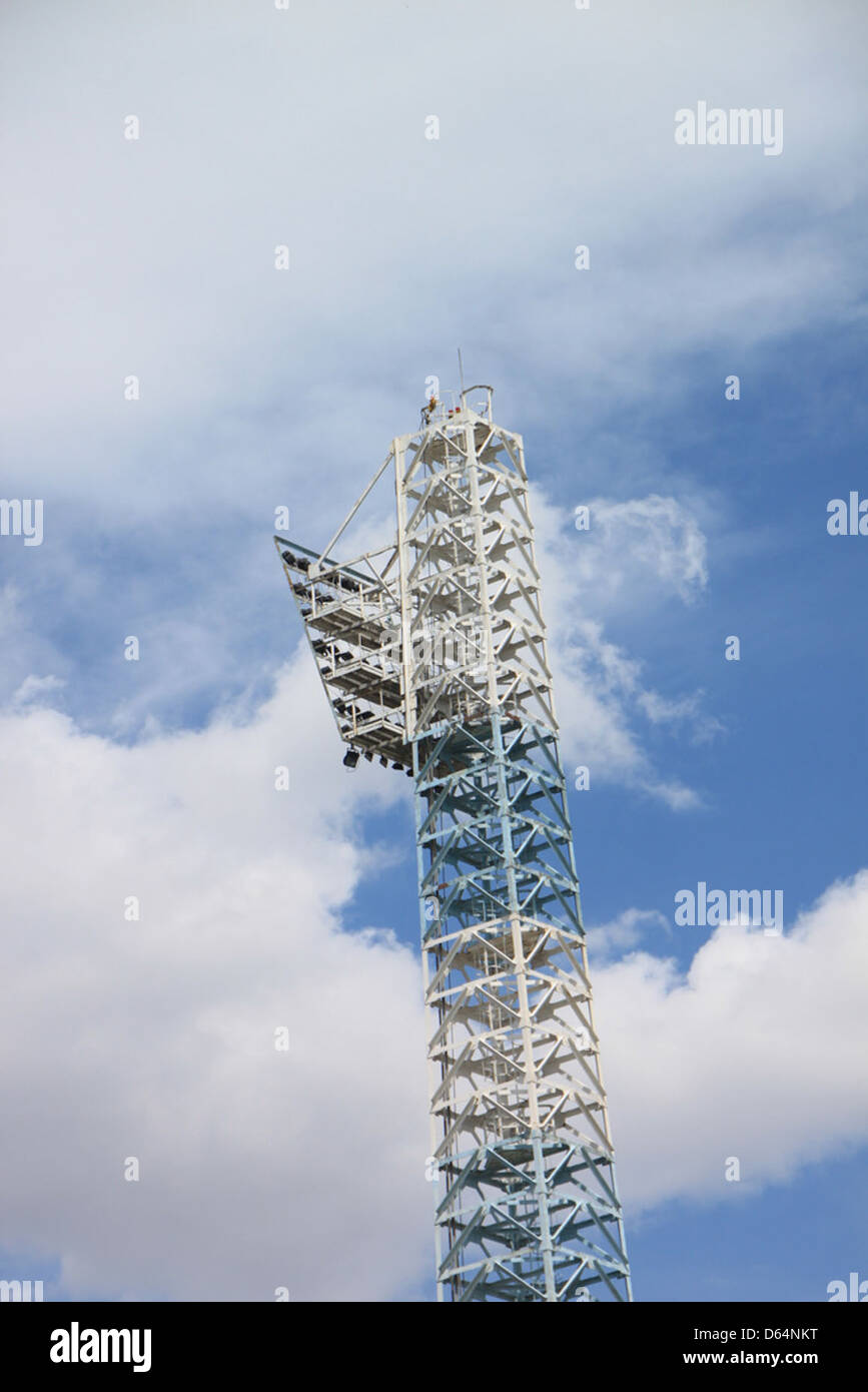 A row of stadium light poles with arrays of bright lamps illuminating a ...