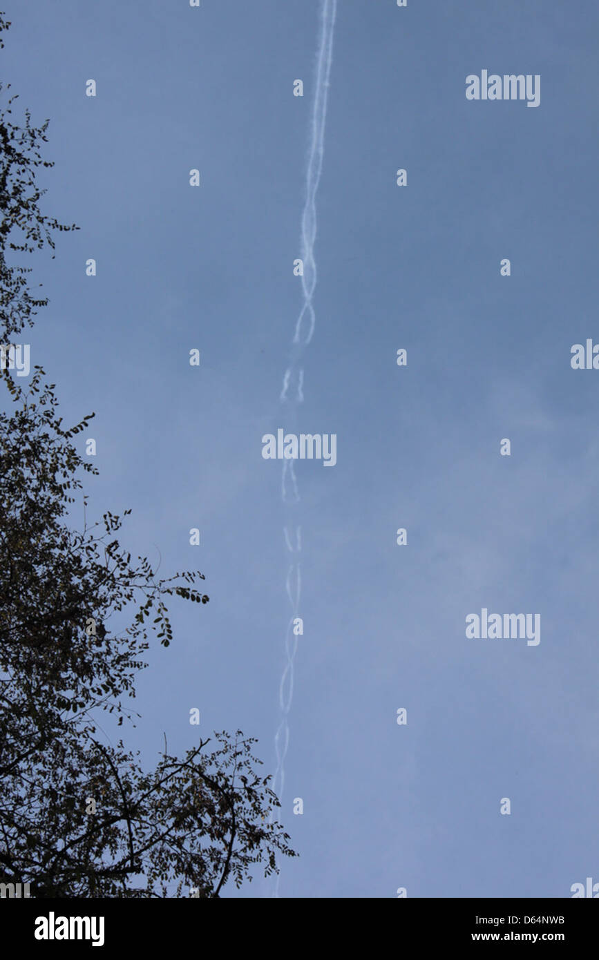 This image features an airplane creating a smoke trail across the sky ...