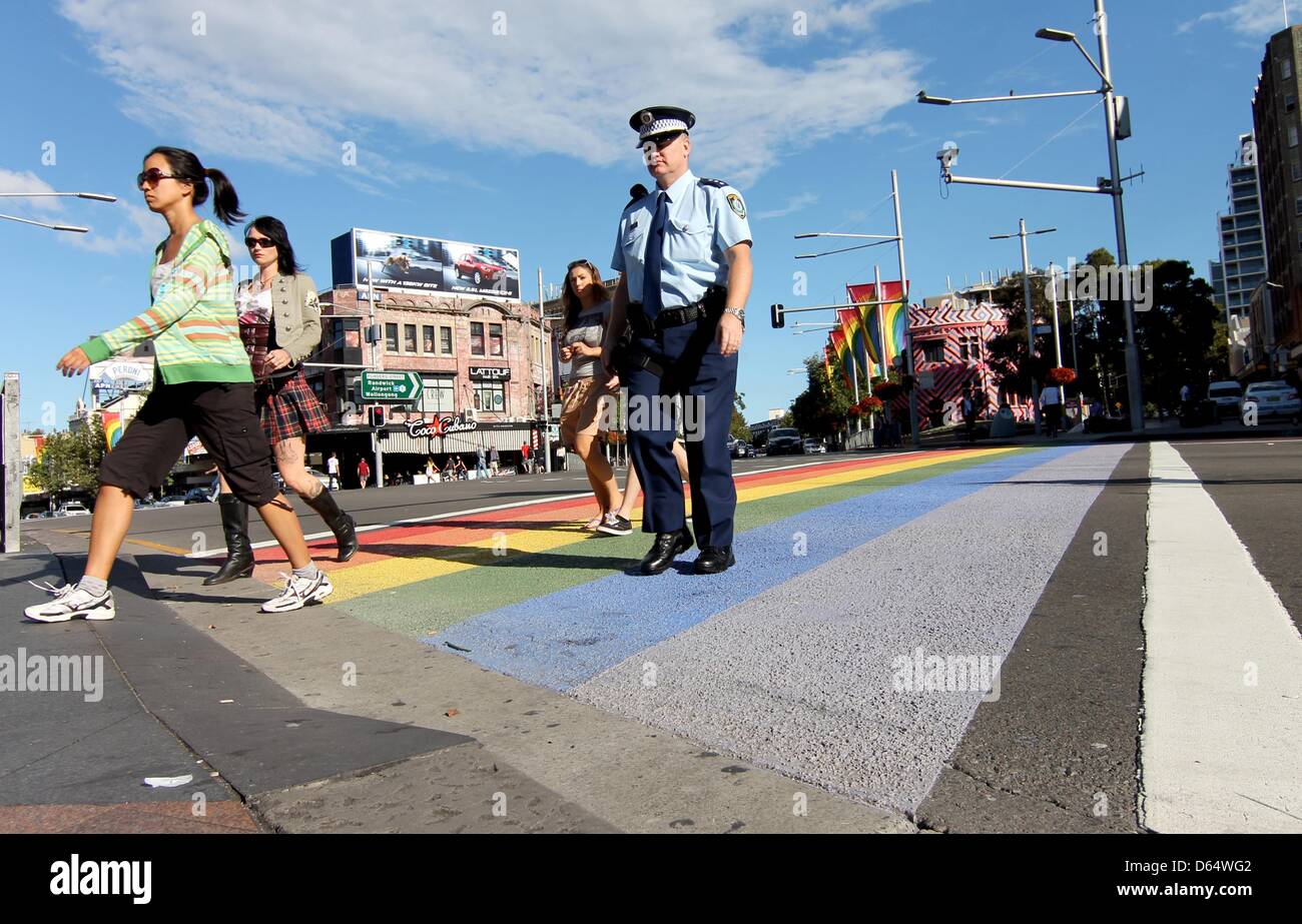 Pedestrians and a police officer cross a street via a rainbow-colored ...