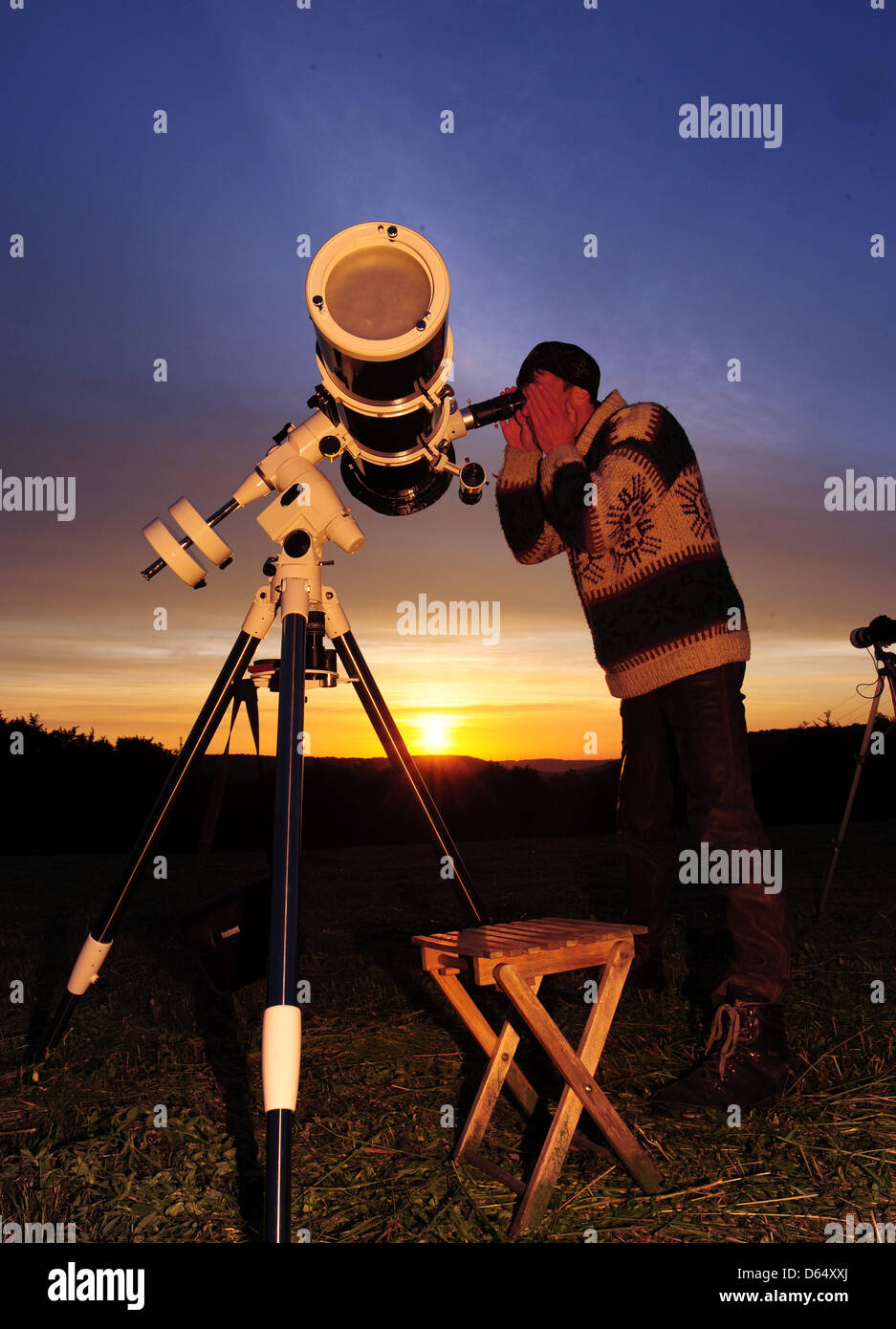 A hobby astronomer points his telescope at the yello disk of the rising ...