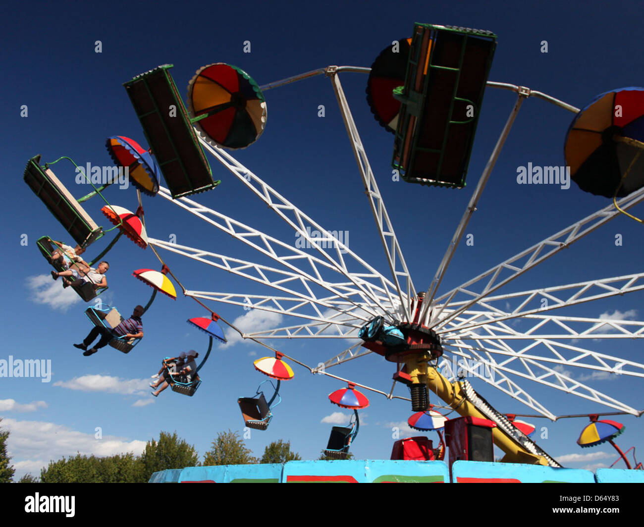 This image shows a wave swing carousel ride against a deep blue sky ...