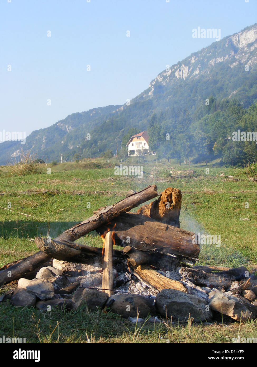 A romantic mountain campfire scene, showcasing a cozy fire surrounded ...