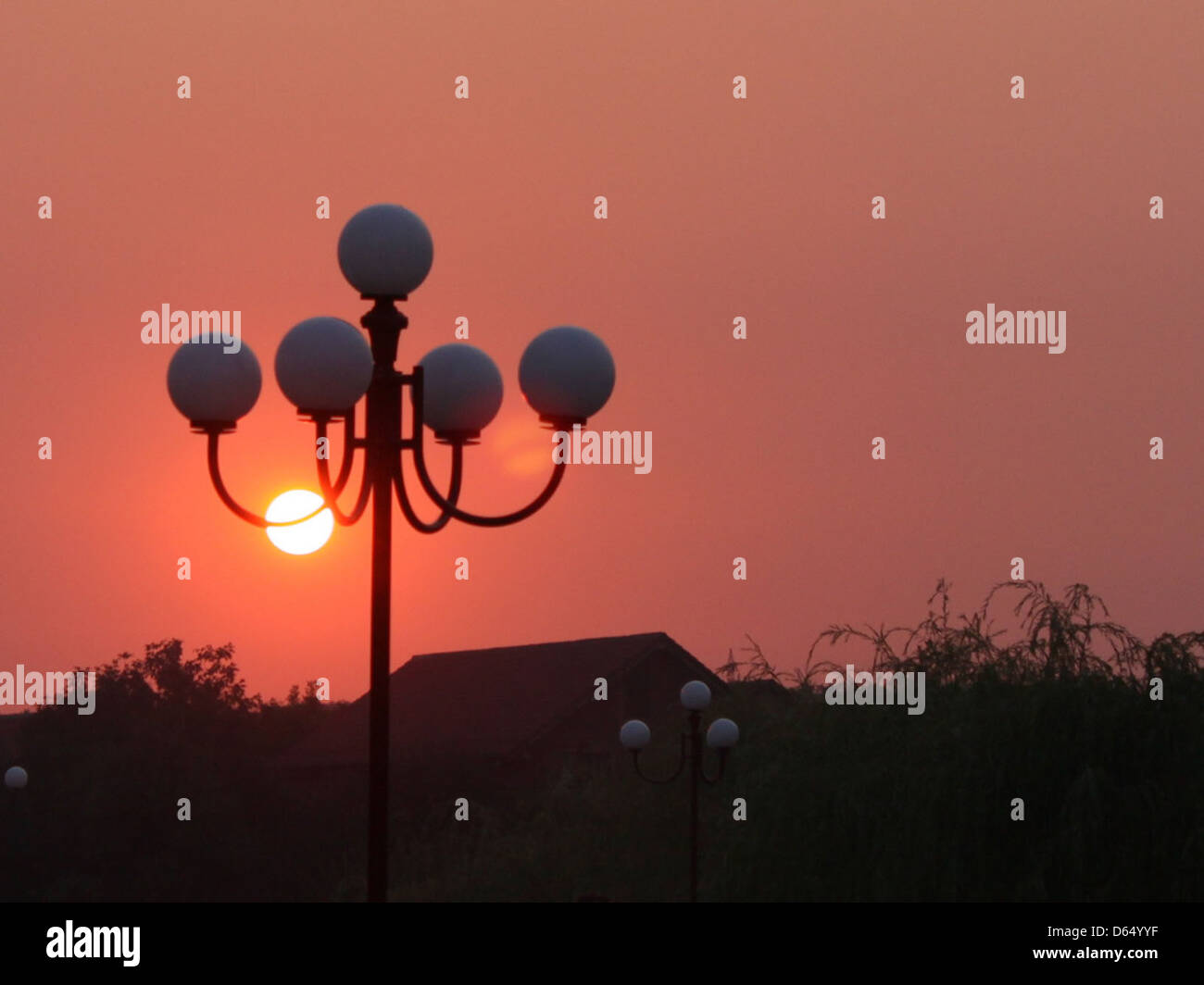 This image features a decorative street lighting pole set against a red ...