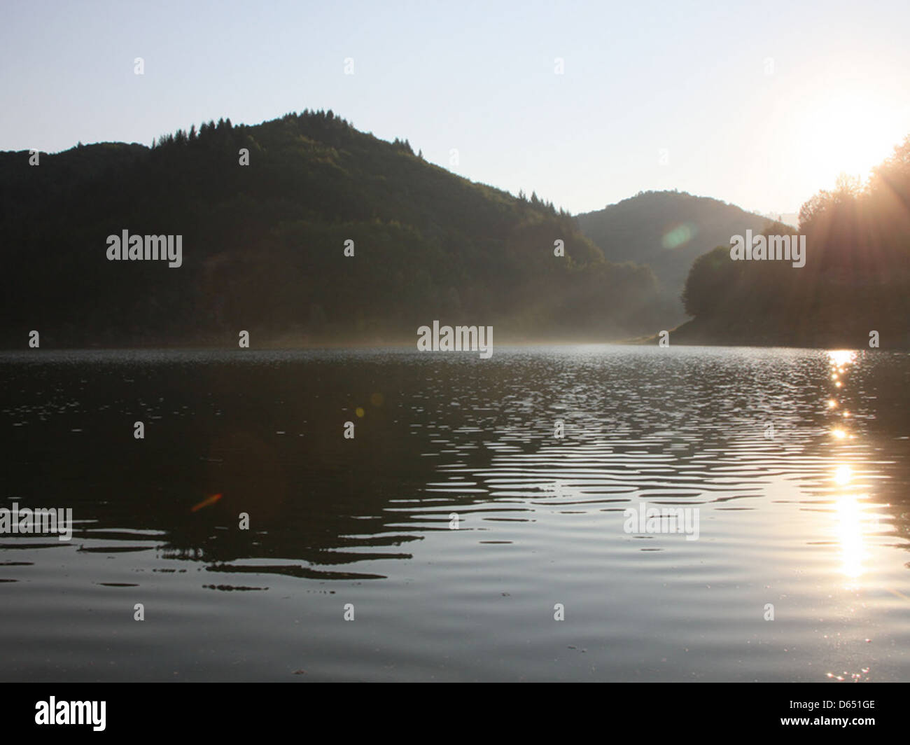 A serene scene of mist rising over a lake at sunrise. The soft mist ...