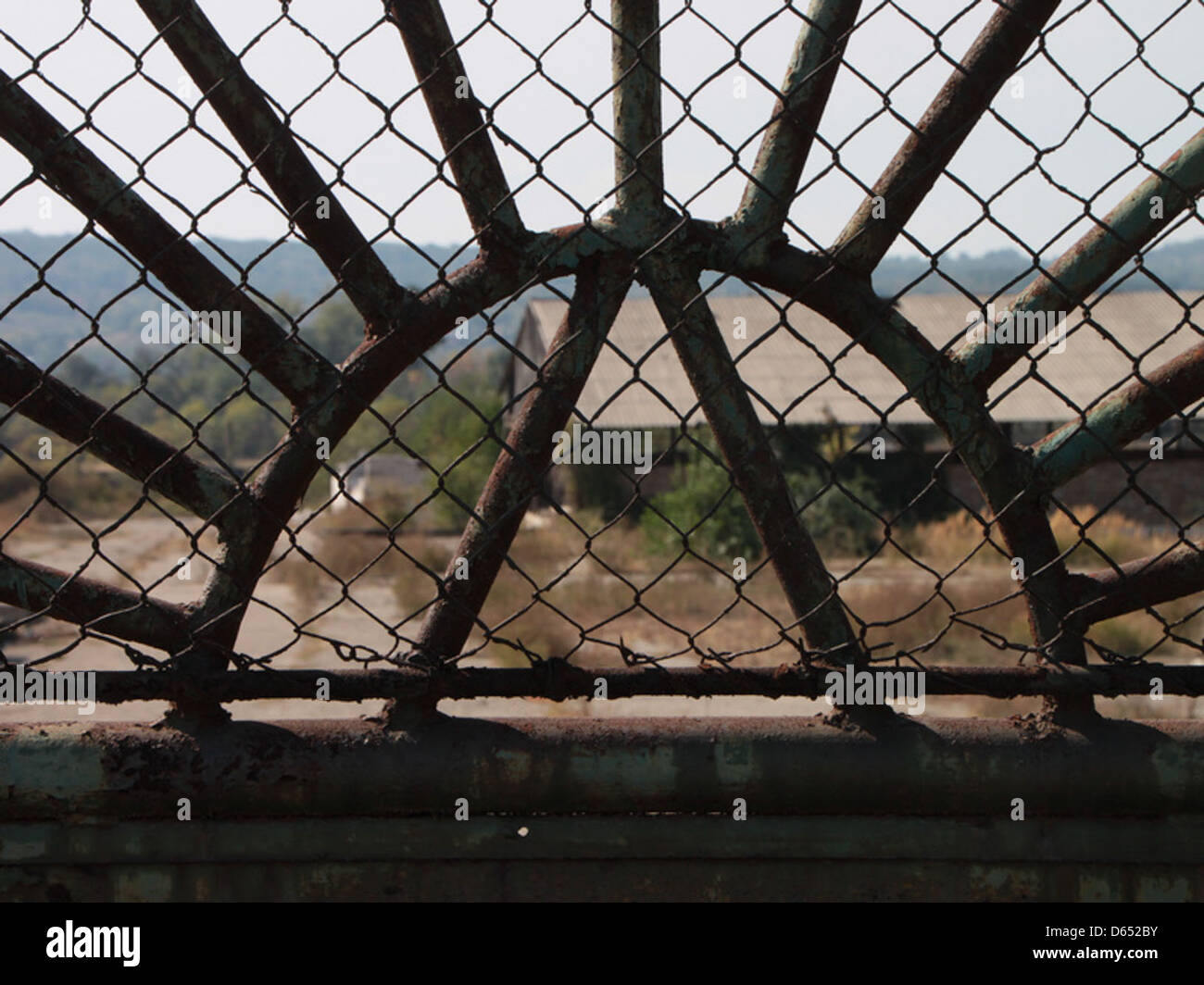 The image depicts old, rusty gates at an abandoned place. The scene ...