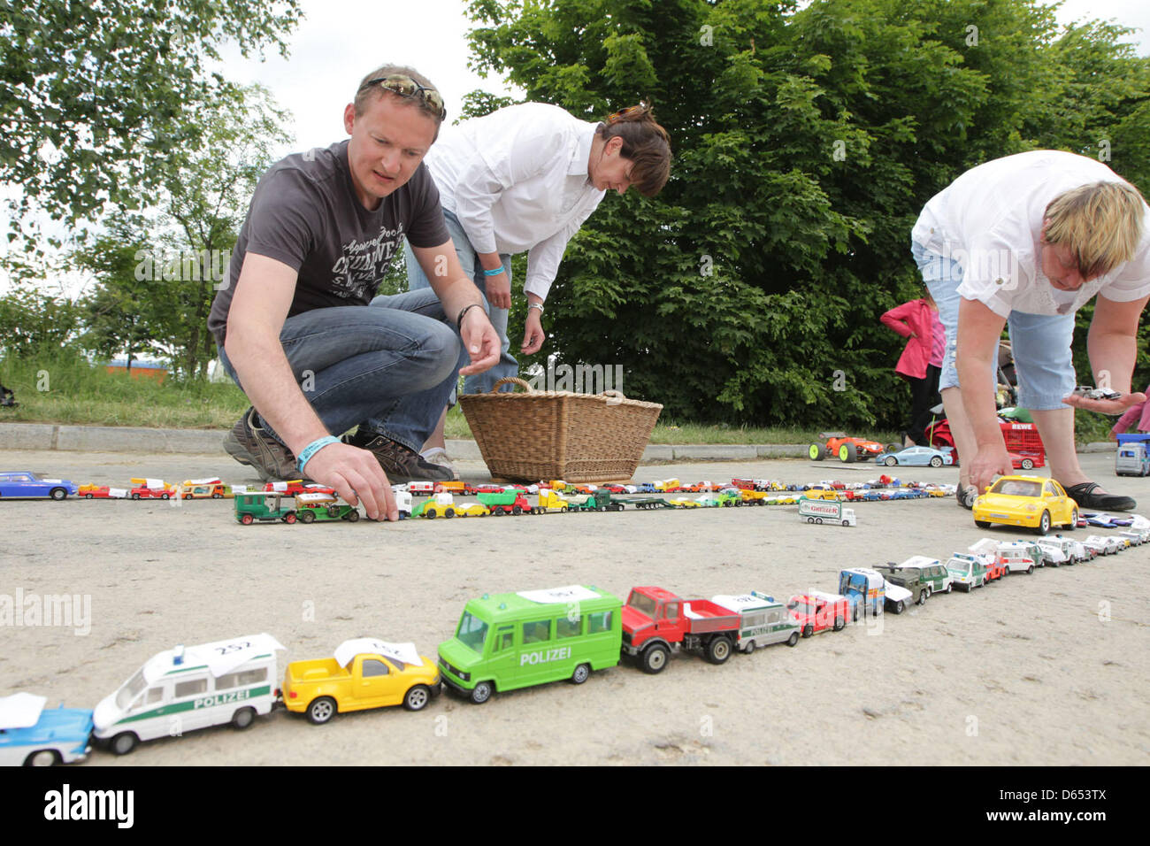 Participants of a world record challenge observe a line of toy cars in ...