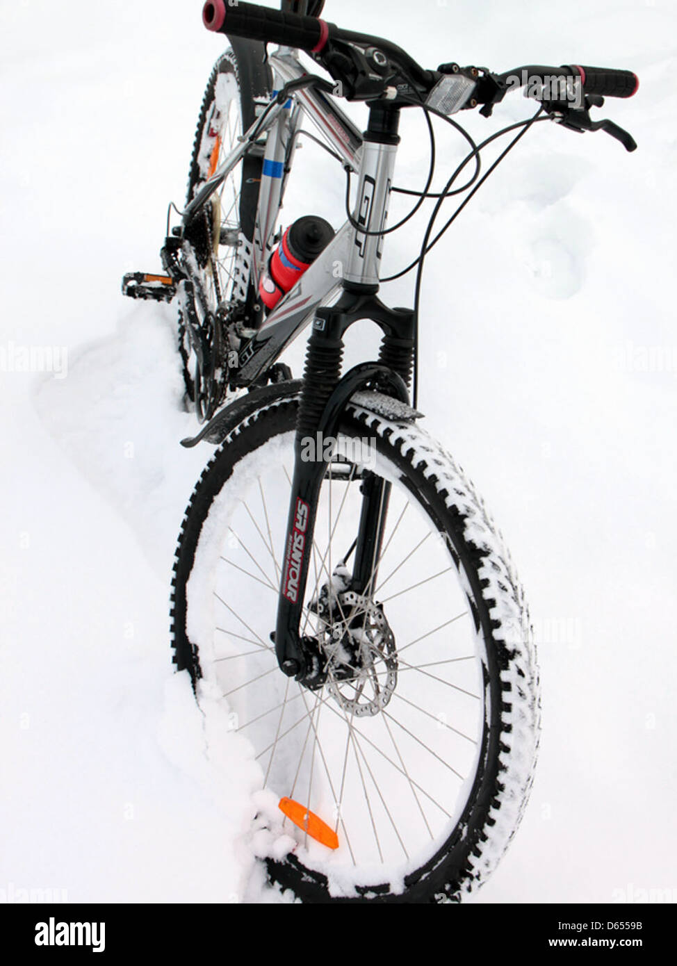 A mountain bike in the snow during a cold winter day. The bike is ...