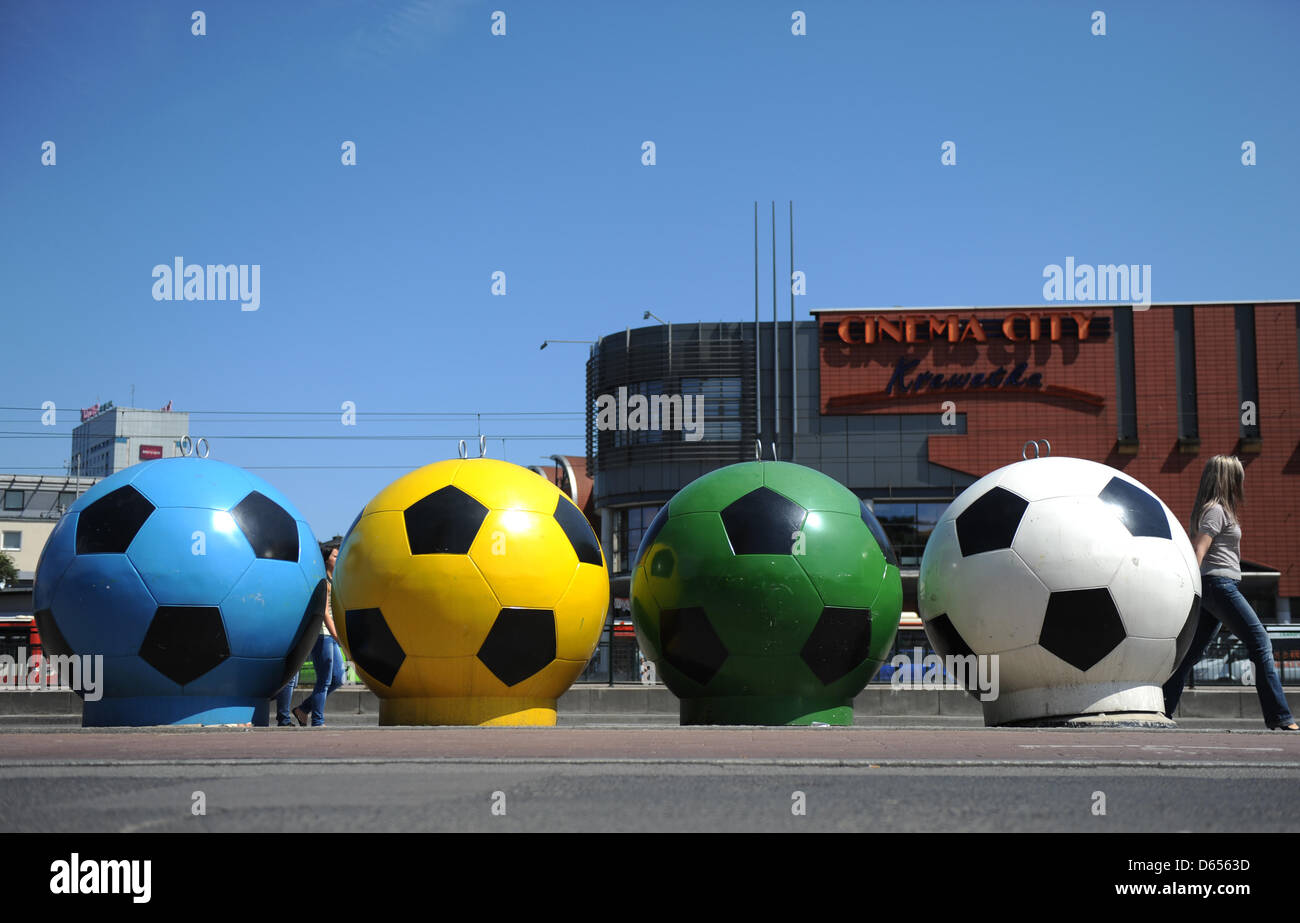 A woman walks past rubbish containers in the shape of footballs in ...