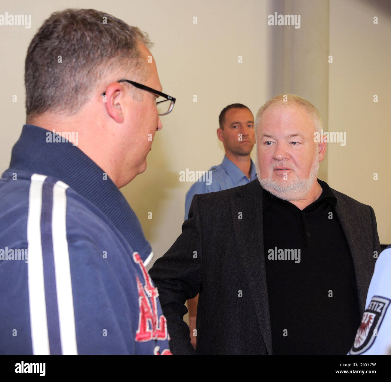 A court bailiff shows hotelier Axel Hilpert (R) talks with his son in a ...
