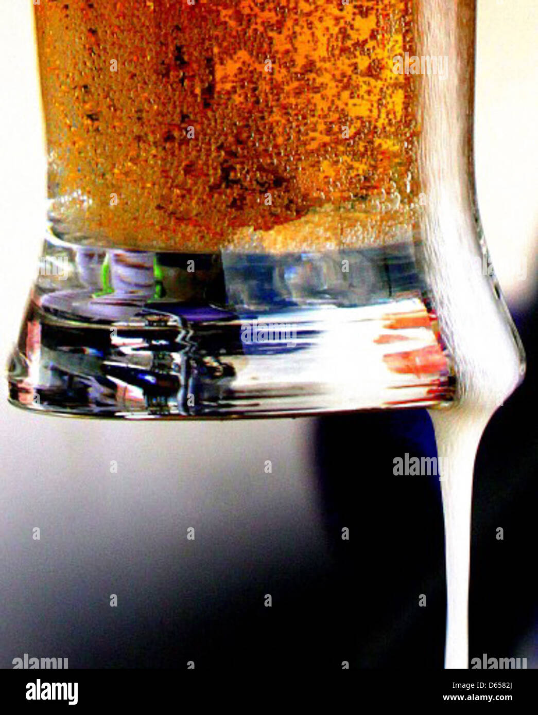 A close-up image of a glass of beer with foam sliding down the sides ...