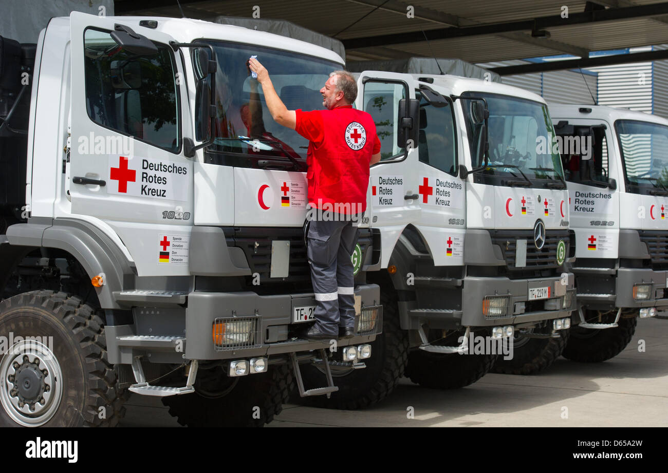 Helpers of the German Red Cross DRK prepare the transport of three ...