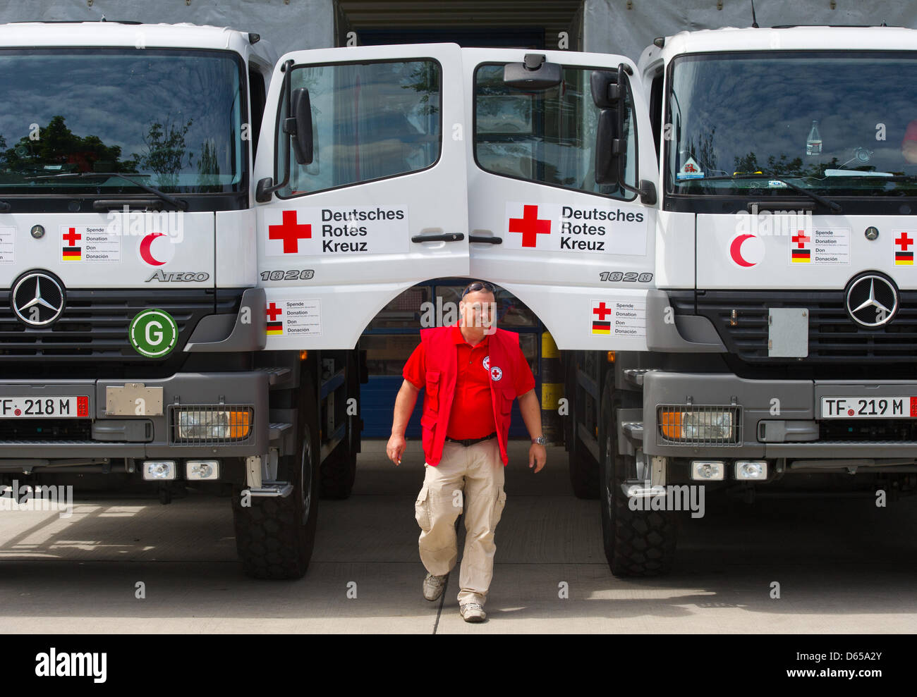 Helpers of the German Red Cross DRK prepare the transport of three ...