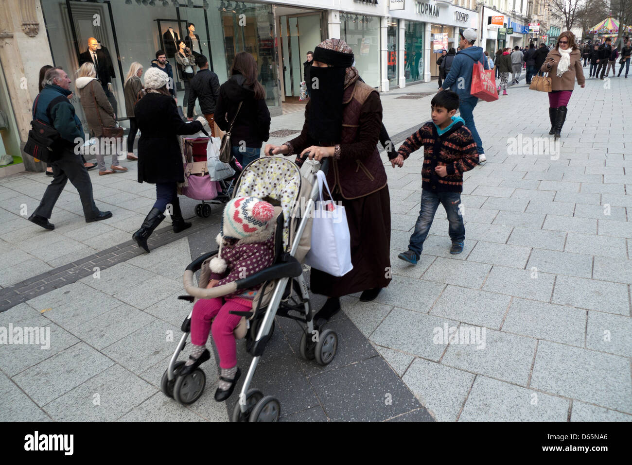 A Muslim woman with children wearing a burqa veil pushing baby buggy ...