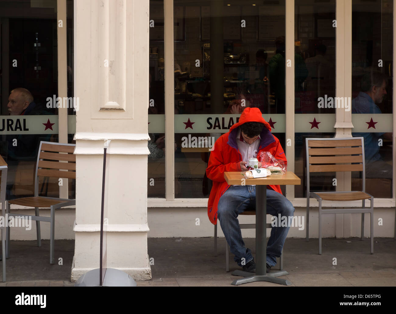 Lone snacker eating lunch outside of café in Cambridge city England ...