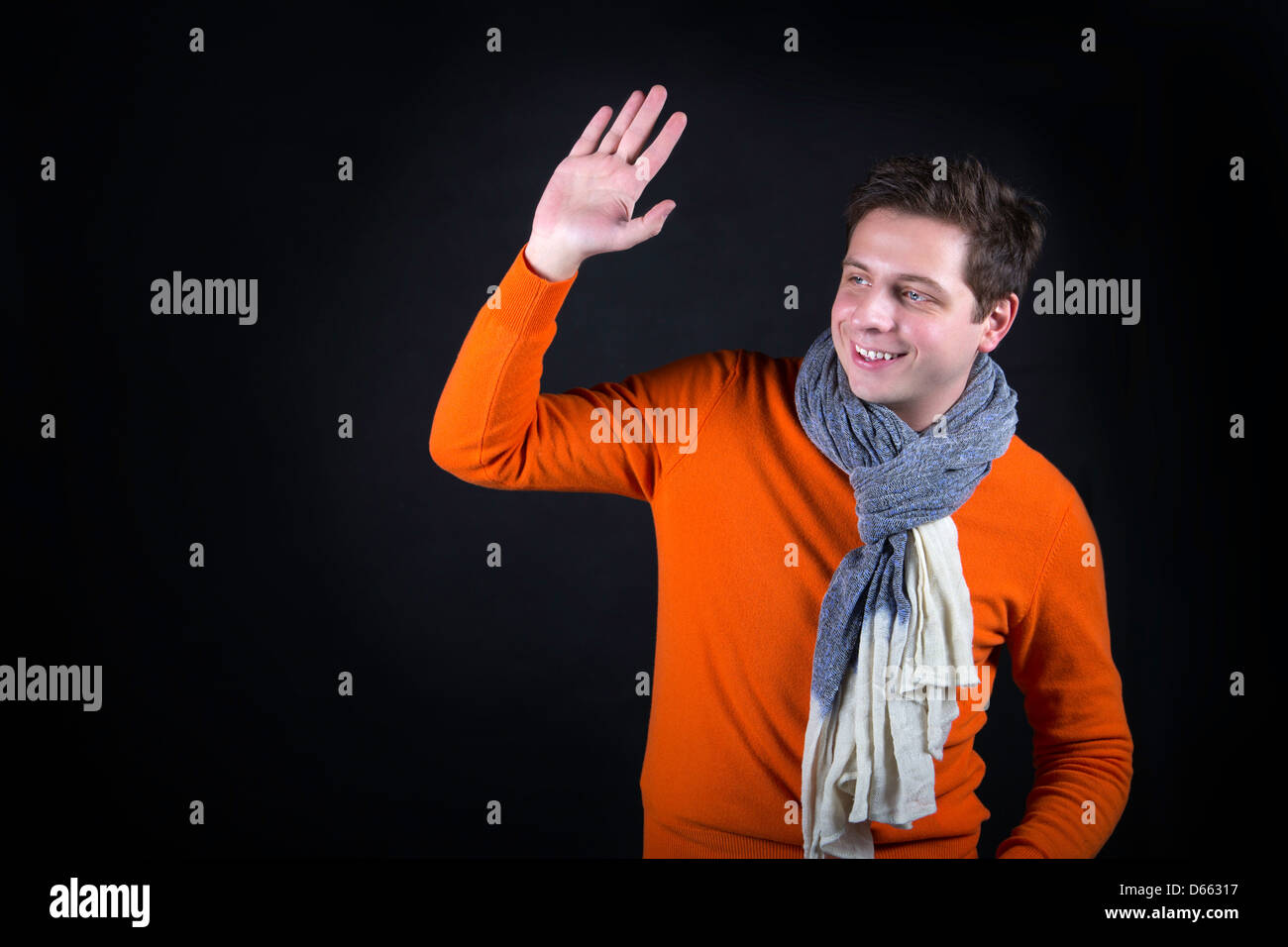 Man on black background greeting someone outside frame Stock Photo - Alamy