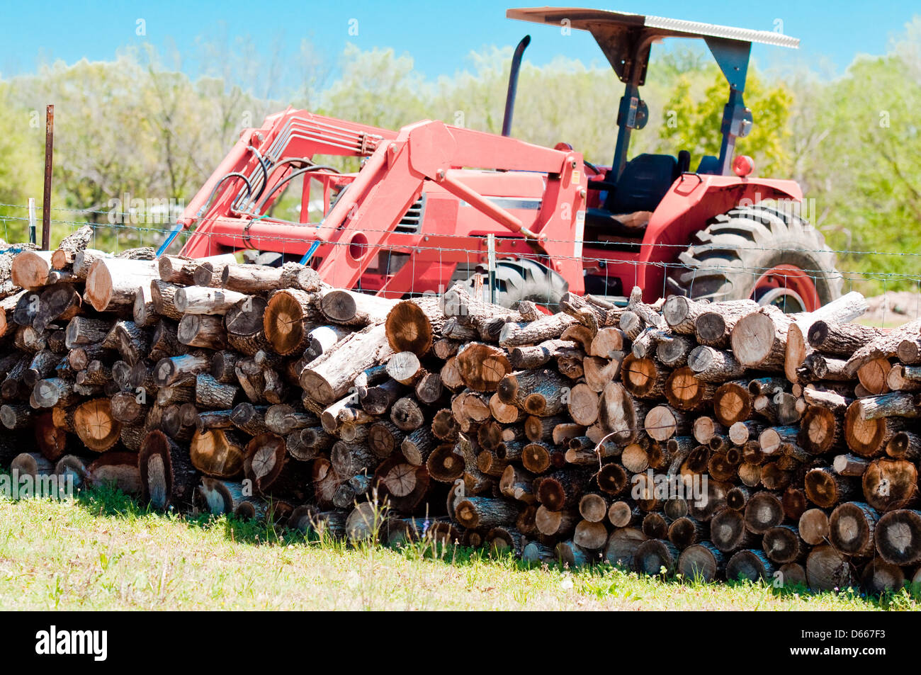 Stack of firewood with tractor in background Stock Photo - Alamy