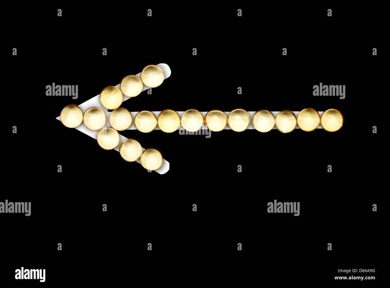 Arrow from yellow capsules on a black background Stock Photo - Alamy