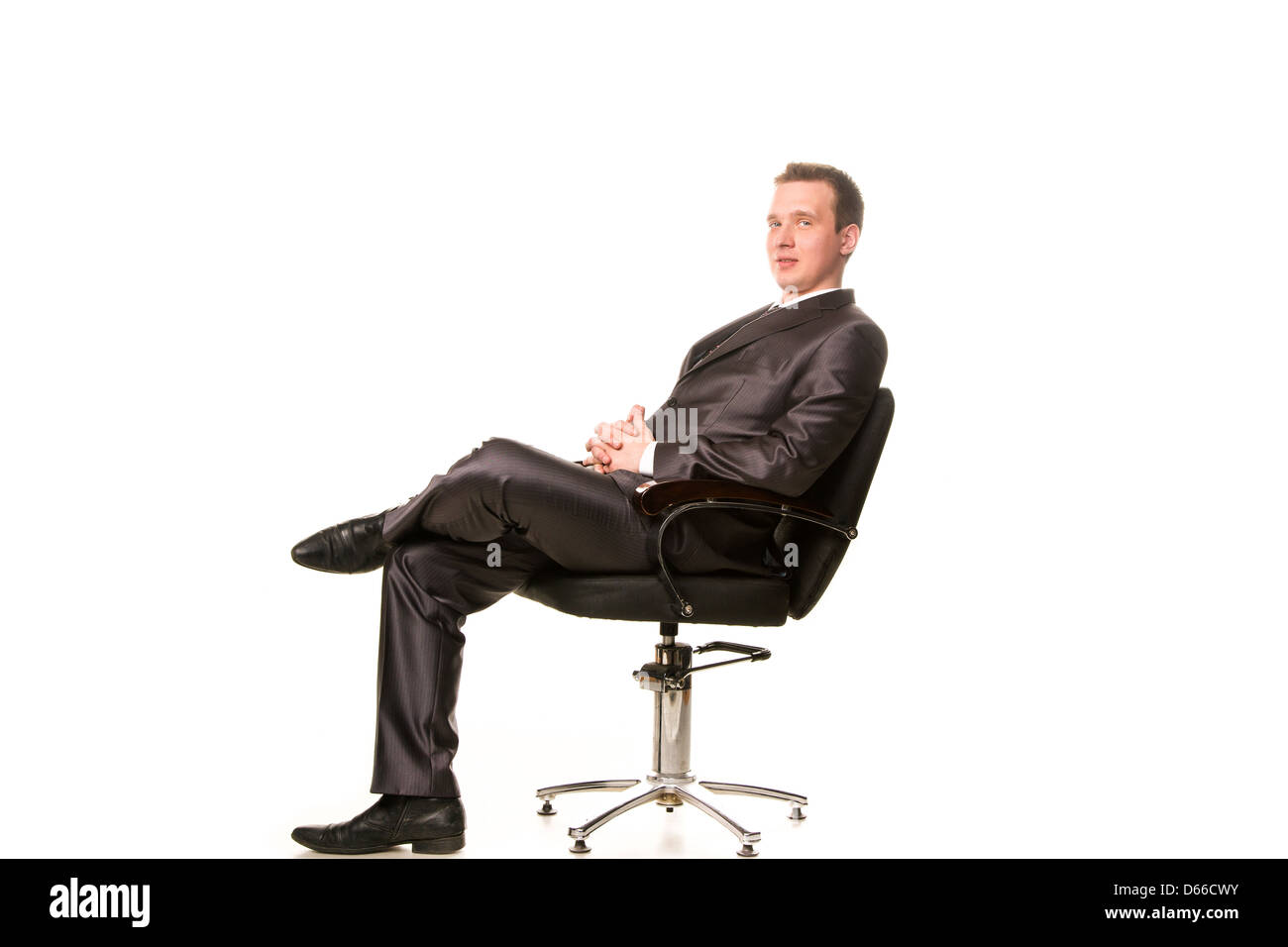 Confident smiling young businessman sitting on a chair isolated on ...