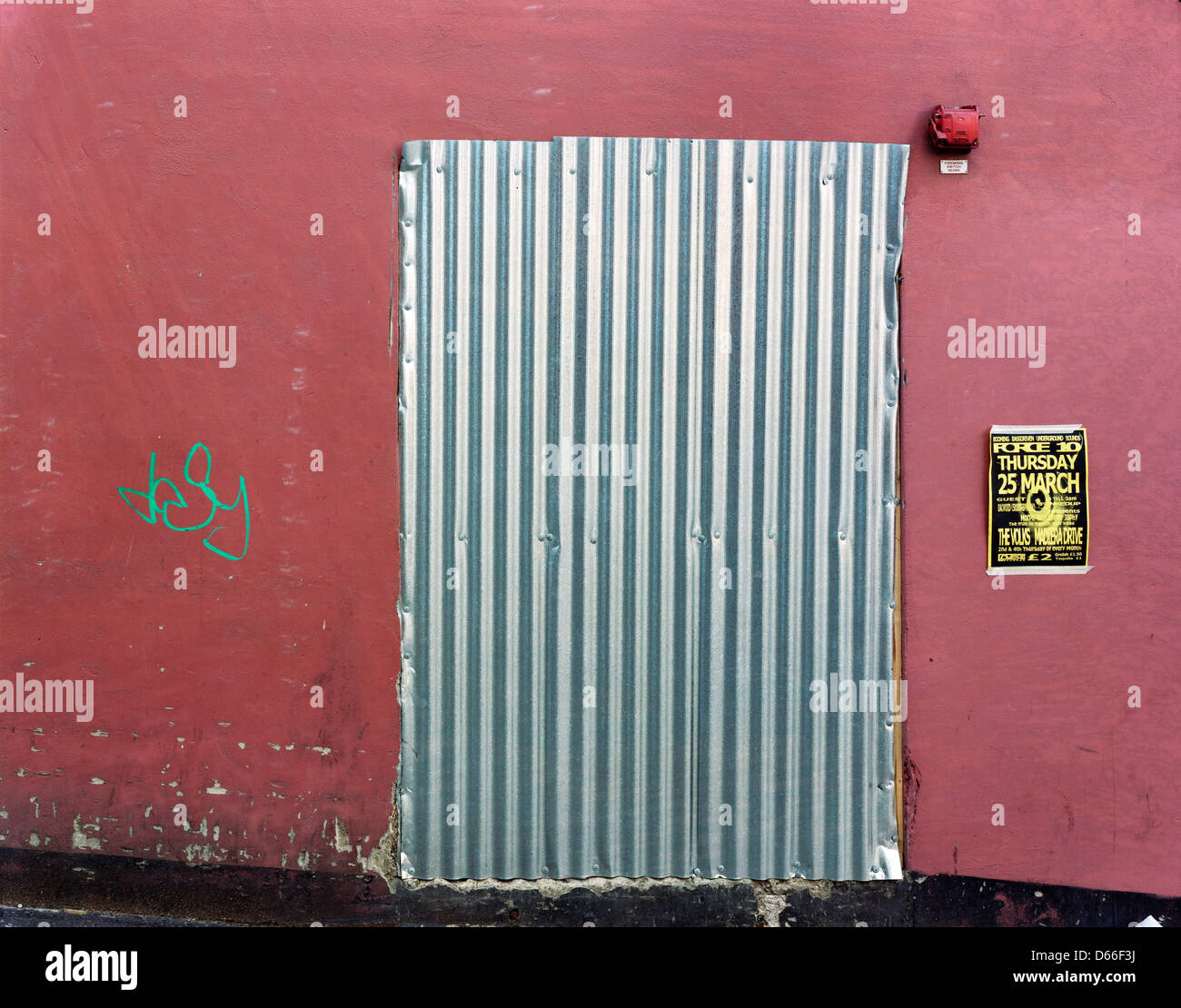 Corrugated iron panel in red wall, Brighton, UK Stock Photo - Alamy