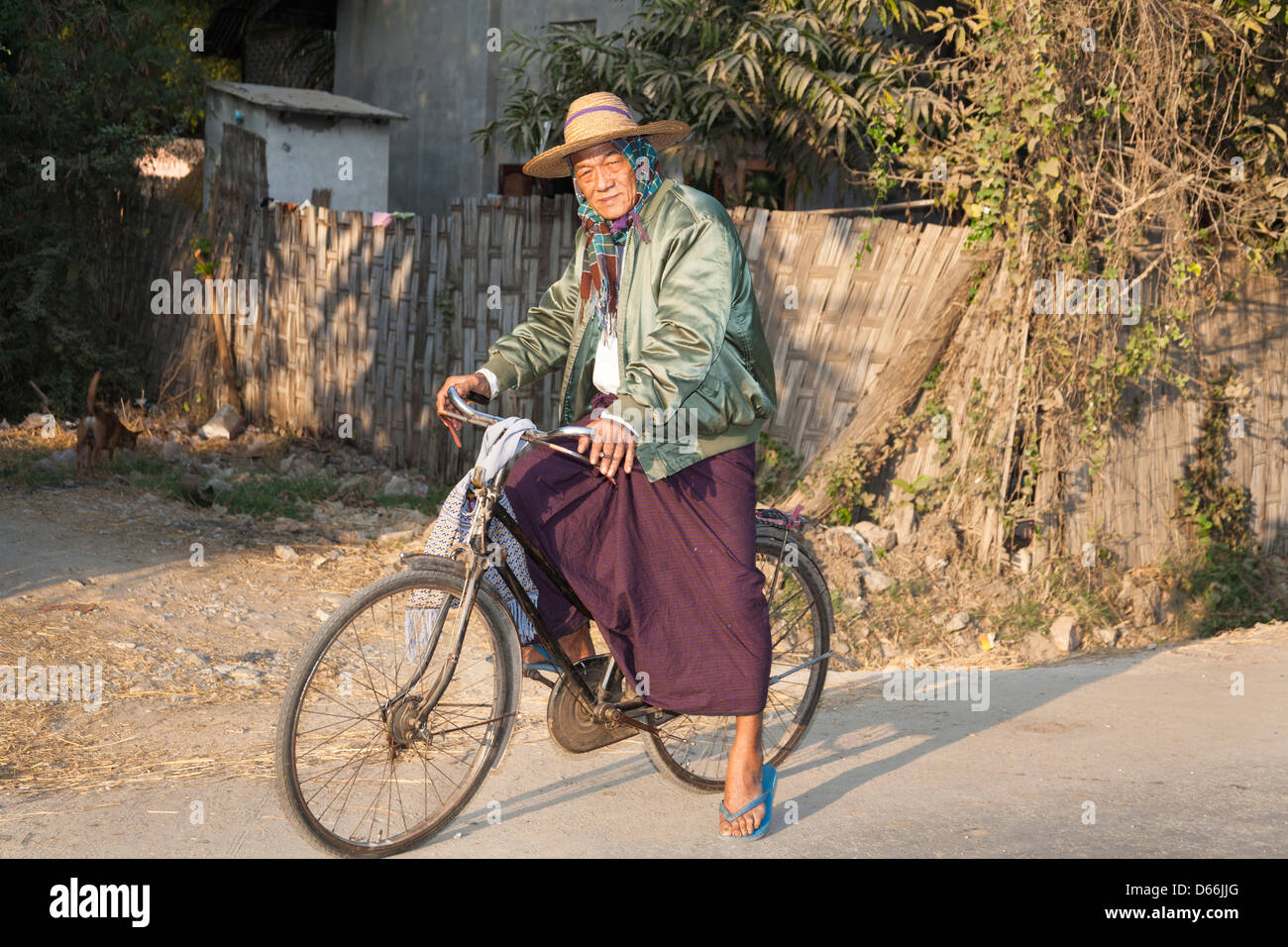 Man riding a bicycle wearing a longyi, Yay Kyi village, Mandalay ...