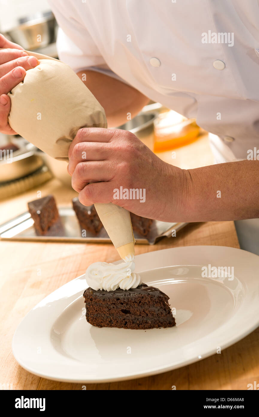 Cook decorating cake with whipped cream with piping technique Stock ...