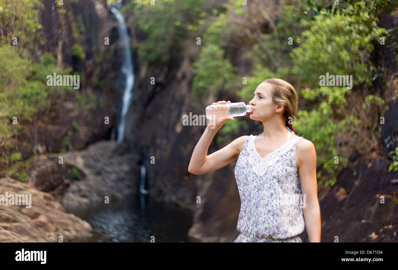 girl drinks water from a bottle on the background of a waterfall Stock ...