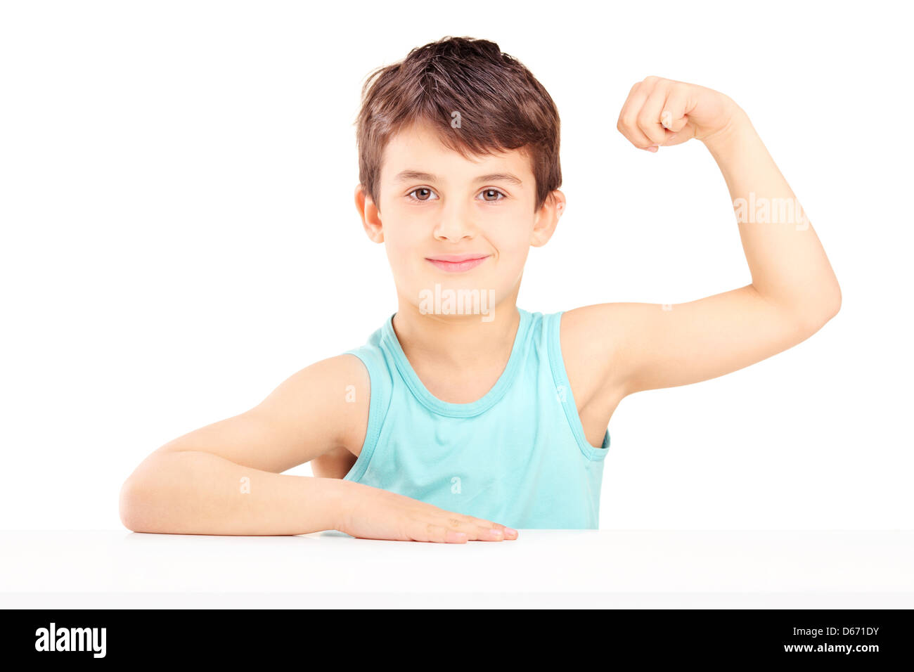 A child showing his muscles seated on a table isolated on white ...