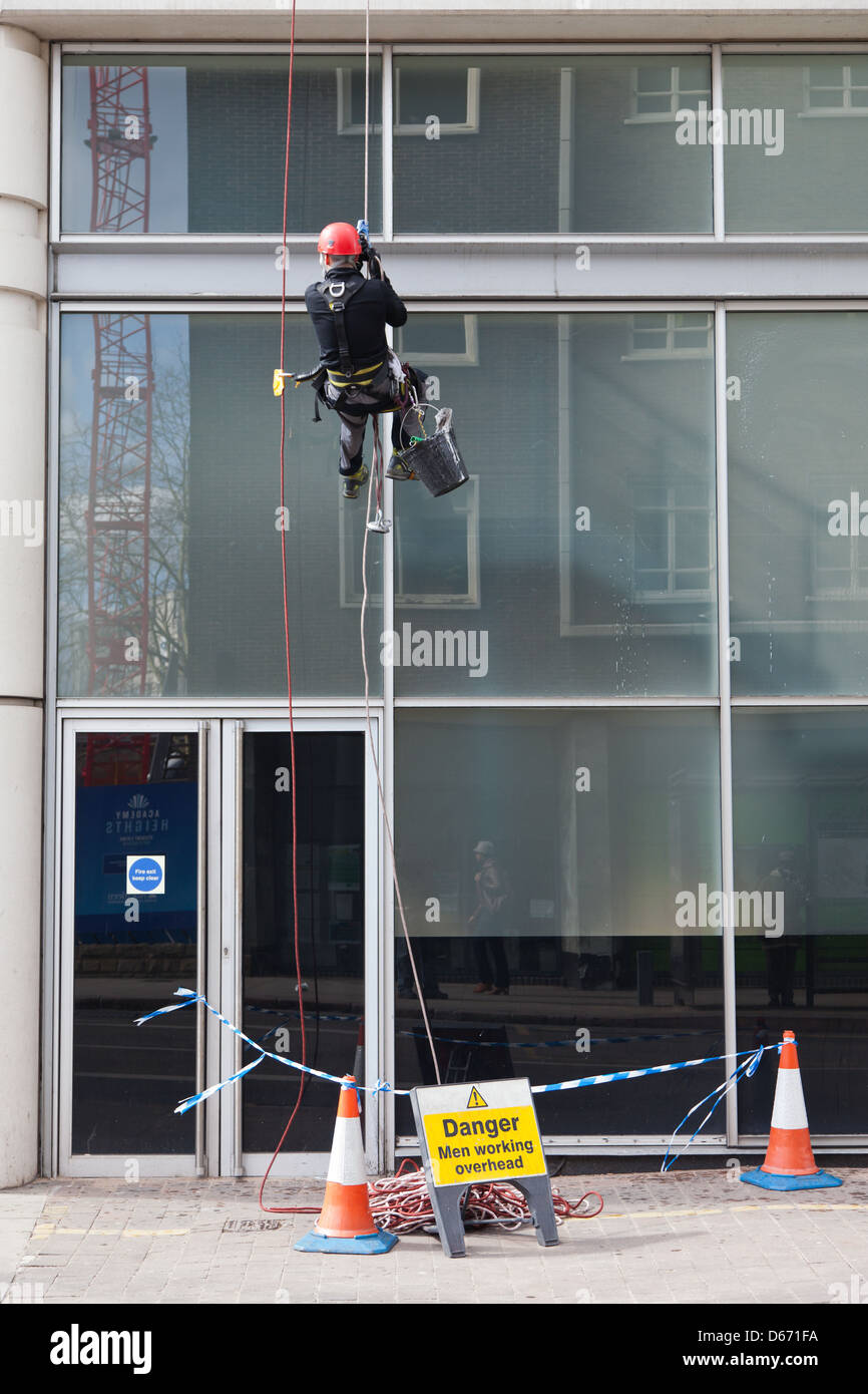 Commercial window cleaner wearing safety equipment cleaning a modern ...