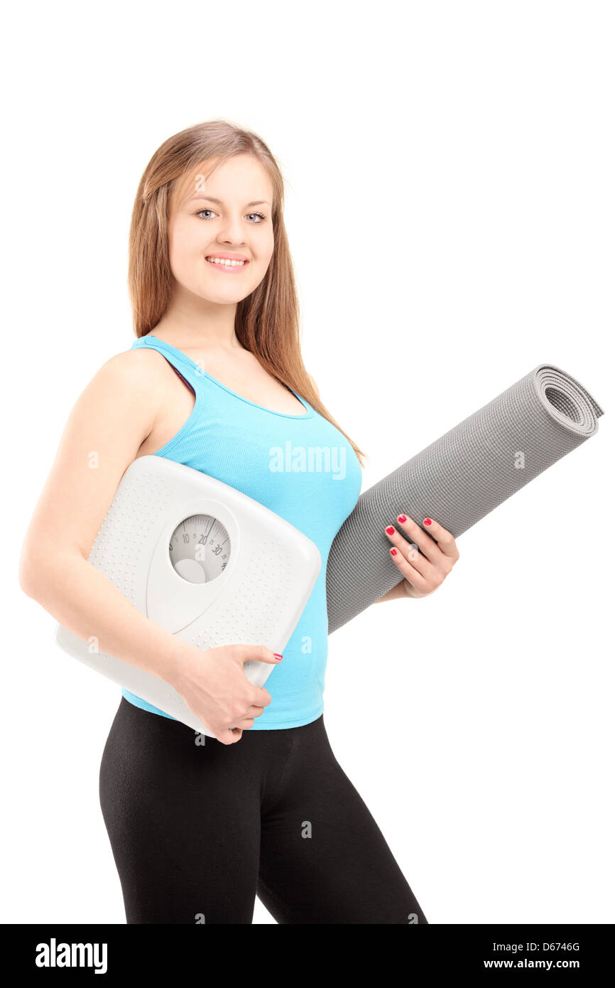 A smiling female athlete holding a weight scale and mat isolated on ...
