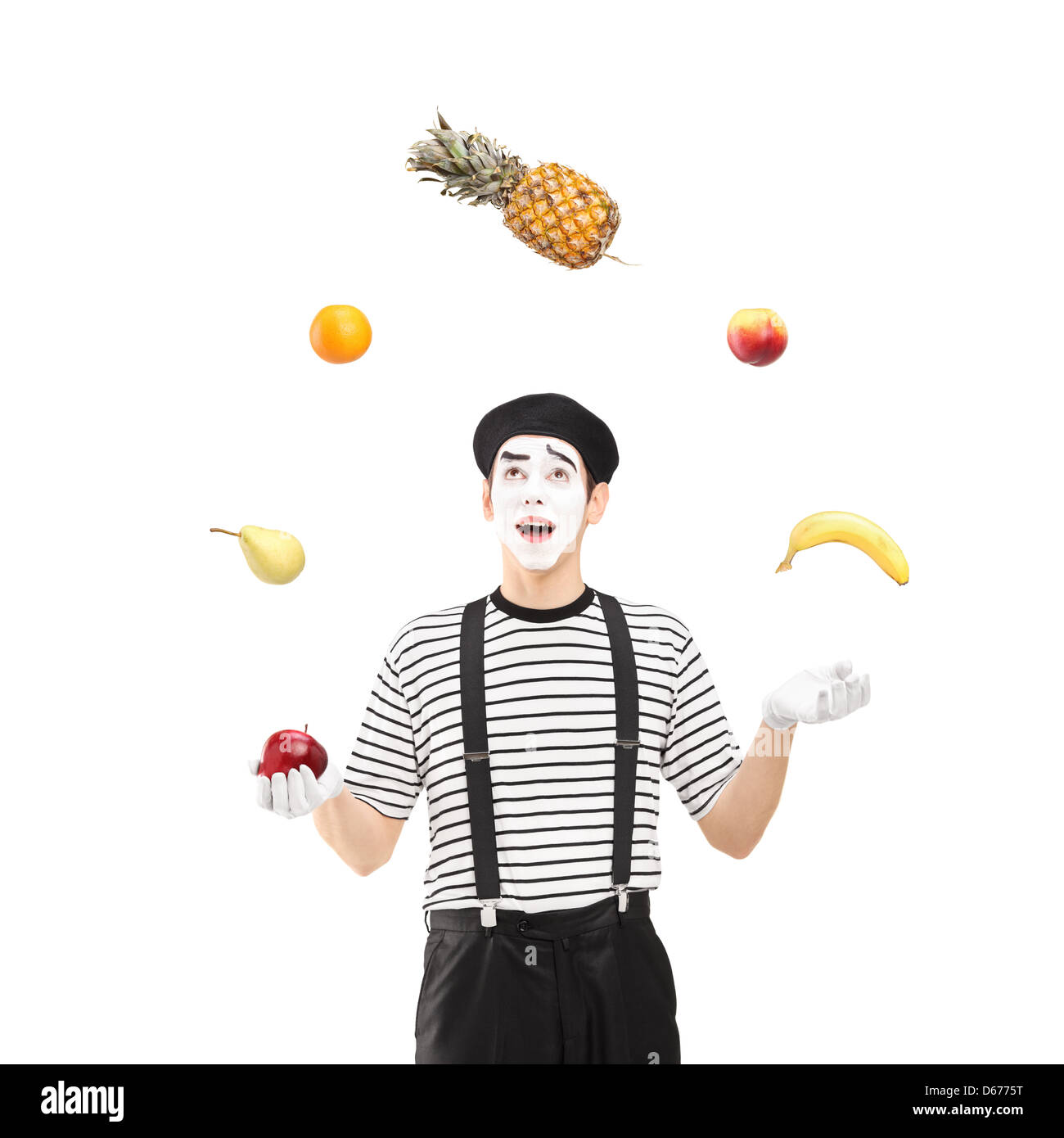 A smiling mime artist juggling fruits isolated against white background ...
