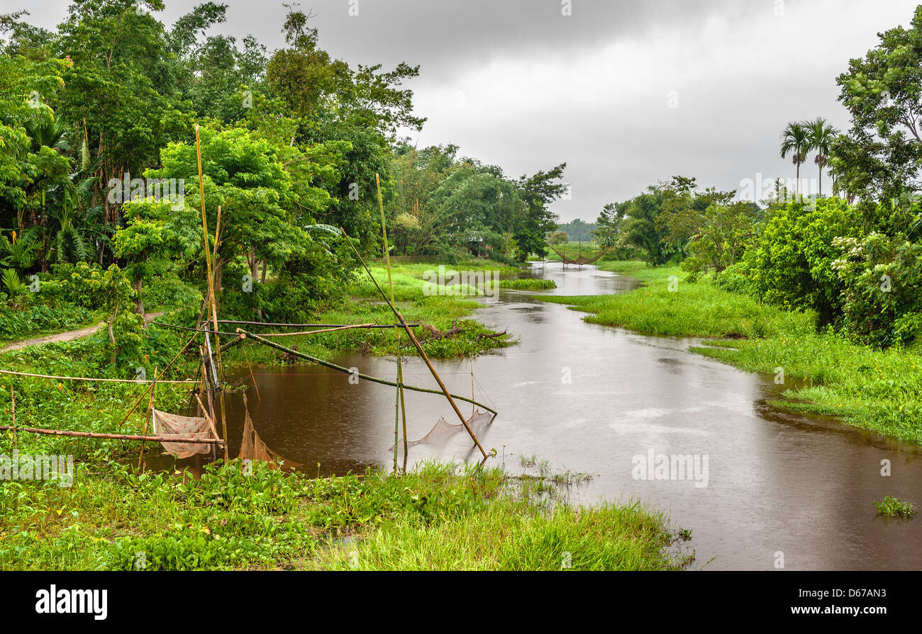 A tributary of the Brahmaputra river flowing through a village near ...