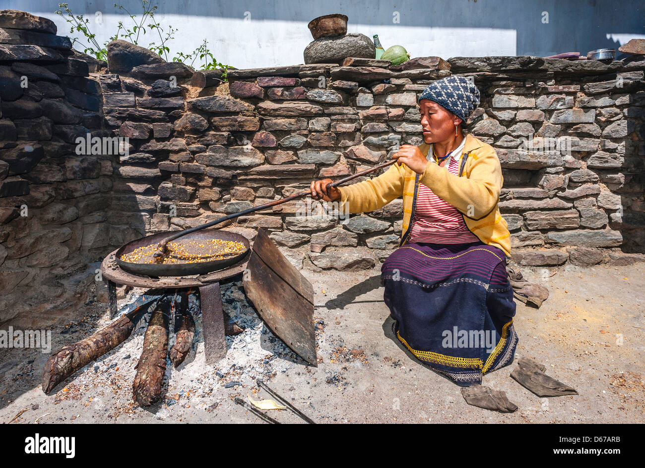 Woman from the Monpa tribe roasts maize on open fire to make a tasty ...