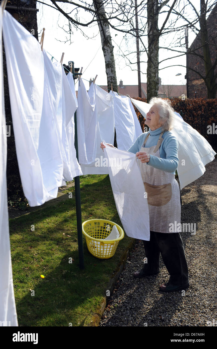 Elderly pensioner hanging out a line of washing on her washing line in ...